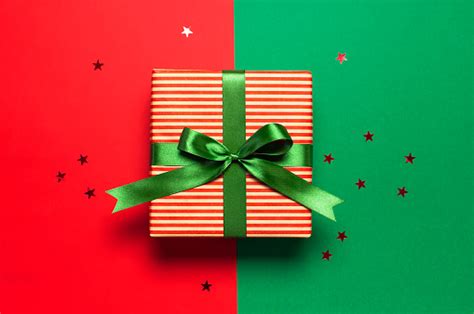 녹색 리본과 홀로그램 반짝이 색종이 붉은 녹색 배경 상단보기에있는 별의 색종이 모양의 선물 상자는 텍스트를위한 공간을 평평하게 놓습니다 휴일 개념 새해 또는 크리스마스 선물