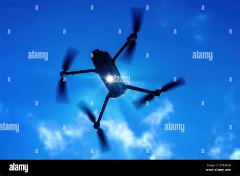 A Drone Soars High Above Spinning Its Propellers In The Vibrant Blue