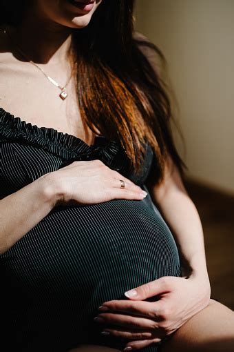 아기를 기다리고 있습니다 임신한 여 자가 앉아 손과 위 둥근 배를 포용 클로즈업입니다 9 개월입니다 베이비 샤워입니다 어머니