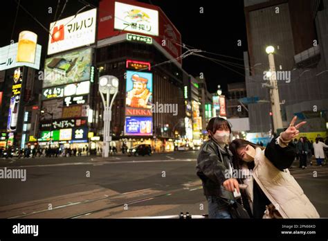 women pose for a photo at a famed traffic intersection in the susukino