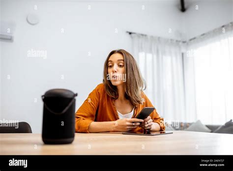Young Cheerful Woman Controlling Home Devices With A Voice Commands Talking To A Smart Column
