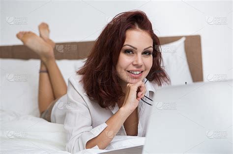 积极的年轻女子躺在床上使用笔记本电脑