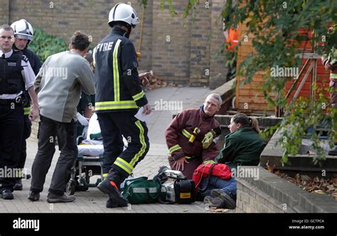 London Fire Brigade Officers In Dark Uniforms Watch As A Private Fire Fighter In Maroon