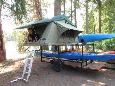 A Tent With Two Kayaks Attached To It And A Ladder In The Foreground
