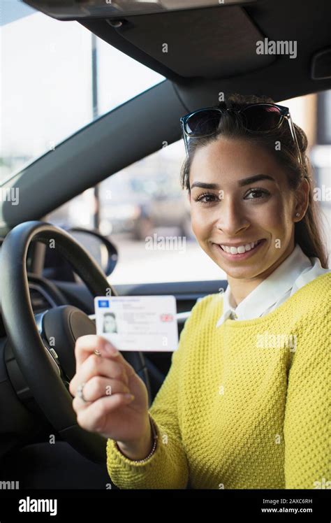 Portrait Happy Young Woman Holding New Drivers License In Car Stock