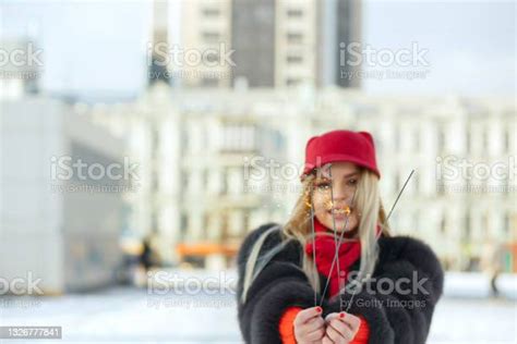 거리에서 스파클러와 함께 크리스마스를 축하하는 세련된 빨간 모자와 스카프를 입은 귀여운 금발 여성 텍스트 공간 20 24세에 대한 스톡 사진 및 기타 이미지 Istock