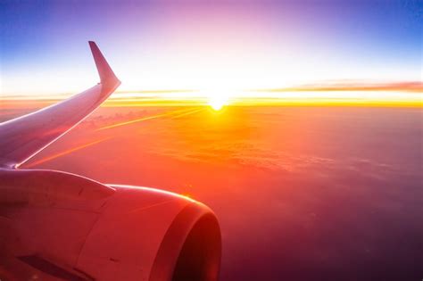 Bela vista aérea da asa de avião na nuvem branca e céu ao pôr do sol Foto Grátis