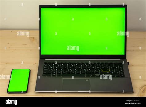 Photo Of Laptop And Smartphone On Wooden Desk Showing Green Screen