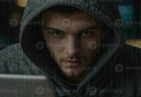 Hacker In A Hoodie Working On Laptop And Curtain Of Green Lines Of