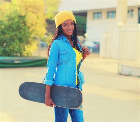 Portrait Of Happy Smiling Young African Woman With Skateboard In The