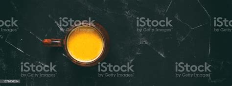 검은 돌 배경에 세라믹 컵에 심황 분말 황금 우유 배너 감기와 독감에 대한 천연 음료 상단 보기 복사 공간 가루로 빻은에 대한