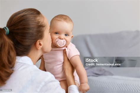 집에서 어린 딸과 놀고있는 어두운 머리 여자와 사랑스러운 여성의 측면 보기 초상화 어머니는 그녀의 아기에게 키스 사랑과 관심