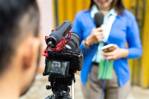 a cameraman recording the beautiful reporter using one set of camera