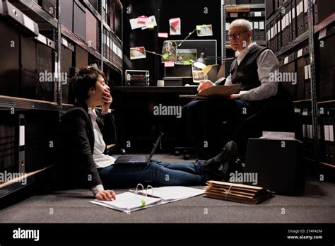 Police Officers Working Overhours At Missing Person Case Analyzing Victim Report In Dark Room