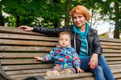 Hermosa Niña Madre Con Un Hijo En El Parque En El Parque Está Sentada En Un Banco Foto Premium