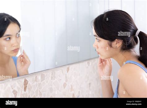 Applying Cotton Pad Asian Woman Treating Blemishes At Bathroom Vanity