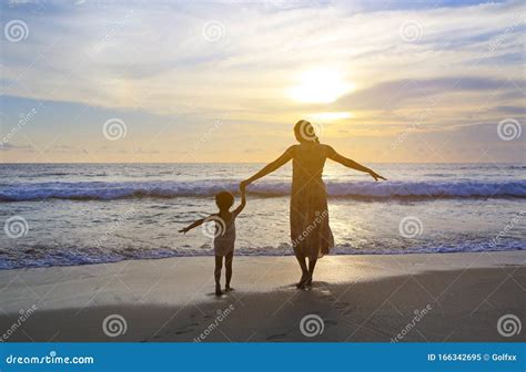 Madre E Hija De Silhouette Jugando En La Playa Al Atardecer Imagen De