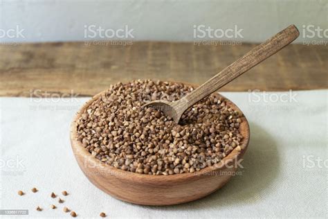 나무 테이블에 린넨 냅킨에 숟가락을 얹은 나무 그릇에 유기농 메밀 이 클로즈업 소박한 스타일 건강한 영양 개념 가로 방향입니다