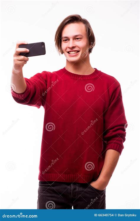 Красивый молодой человек в красном свитере держа камеру и делая Selfie