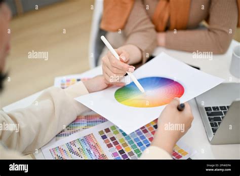 Close Up Image Of Two Female Graphic Designers Choosing Color From Color Swatch Sample