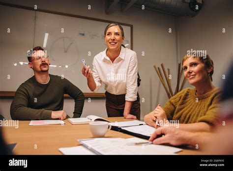 Female Entrepreneur Explaining New Working Strategies To Team Members