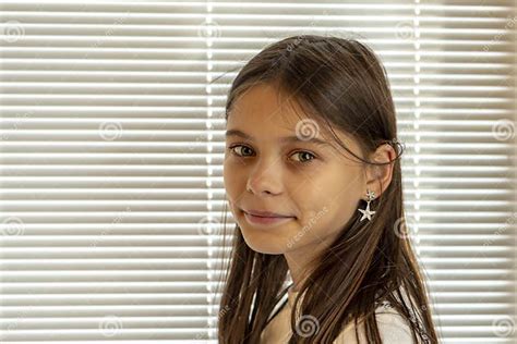 A Beautiful 11 Year Old Girl Against The Background Of Window Blinds
