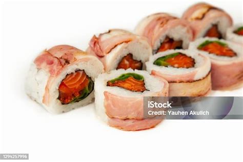 흰 배경에 베이컨과 연어를 곁들인 스시 롤 베이컨 연어 파 날아다니는 생선 알 빙산 소스 쌀 노리를 곁들인 재료 전통 일본 음식