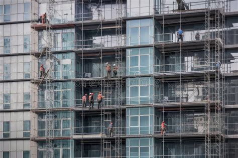 workers installing windows on high rise building with scaffolding and