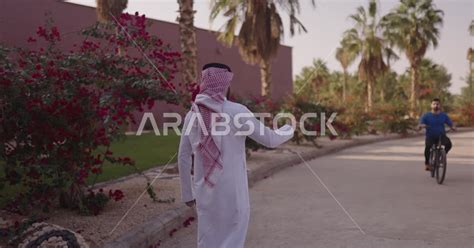 شاب عربي سعودي خليجي يرتدي الزي السعودي التقليدي، يقوم بالتنزه في