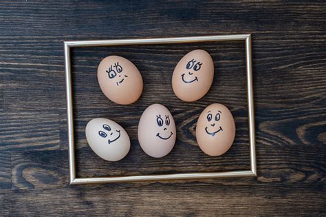 어두운 나무 벽 배경에 미소 황금 프레임과 많은 재미있는 계란을 그림 계란 가족 감정 얼굴 초상화입니다 개념 재미있는 음식