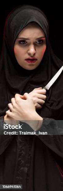 절망의 아름 다운 초상화 무서 워 무서 워 젊은 이슬람 여성 검은 배경에 보호 개념으로 그녀의 손에 칼을 들고 검은 Hijab를