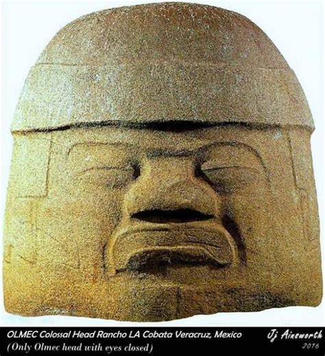 A Large Stone Statue With A Mans Face On It In Front Of A White