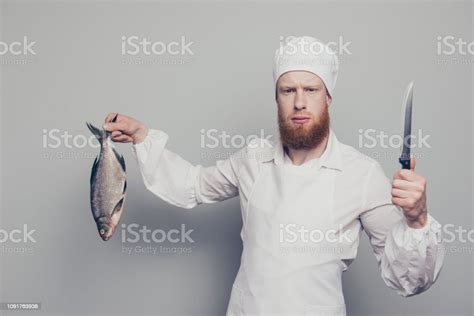 팔 손 해산물 맛 있는 맛 있는 조리법에 회색 파스텔 배경 위에 절연 운반 물고기와 칼을 들고 미친 매력적인 잘생긴 심각한 분노