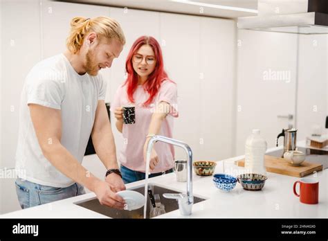 White Man Washing Dishes And Talking With His Her Girlfriend In Kitchen