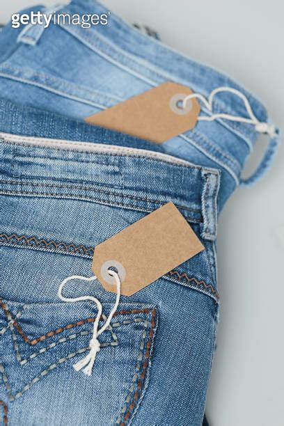 Stack Of Blue Jeans And Empty Tags On White Background