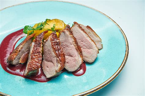 회색 배경에 고립 된 파란색 접시에 베리 소스와 사과를 곁들인 구운 오리 필레를 식욕을 돋우고 있습니다 닫아 0명에 대한 스톡