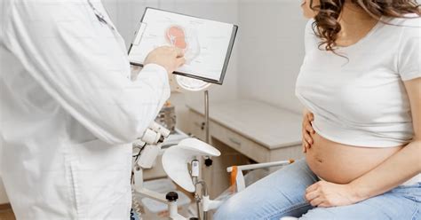 산부인과에서 진료를 받는 임산부와 함께 의사가 이해를 돕기 위해 몇 가지 의료 계획을 보여줍니다 임신 중 의료와 건강의 개념