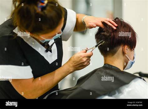 Hair Stylist Wearing Face Mask Cutting And Styling The Hair Of A Dark