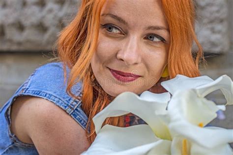 Девушка красивого Redhead кавказская пахнуть красочными цветками в саде