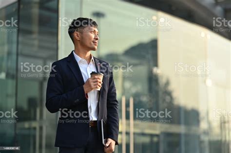 성공한 사업가의 초상화는 이른 아침에 햇빛이 비치는 야외에 서 있는 테이크아웃 커피잔을 들고 있다 남자에 대한 스톡 사진 및