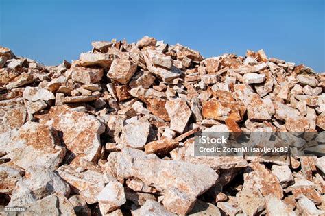 화강암은 갈색 건설 및 여름 시간에 푸른 하늘 아래 더미에 쌓여 바위 바위의 큰 더미 채 석 장에서 석회석의 큰 더미입니다 자갈 및 건축 재료의 더미입니다 갈색에 대한 스톡