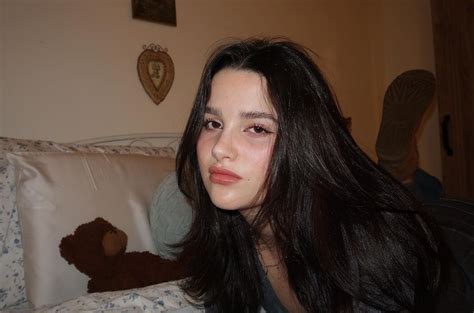 A Woman With Long Black Hair Sitting On A Couch In Front Of A Teddy Bear