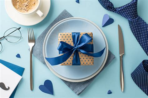 파스텔 블루 배경에 접시 커피 머그잔 수저 냅킨 리본 리본 넥타이 안경 우편 및 하트가 있는 선물 상자가 있는 멋진 아버지의 날 테이블 배열 0명에 대한 스톡 사진 및 기타