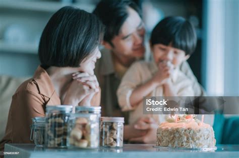 아시아 중국 의 가족 눈 마감 생일 케이크 앞에서 생일 소원을 만들기 전에 거실에서 생일 촛불을 불기 전에 아들 생일을 축하