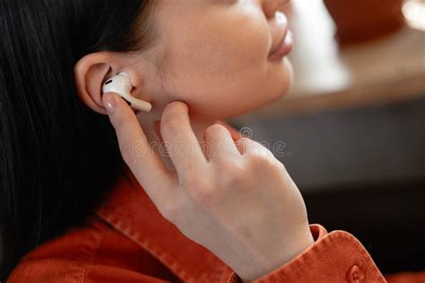 Close Up Of Woman Inserts Earbuds Into Her Ear And Turns Them On To Listen To Music Or For The