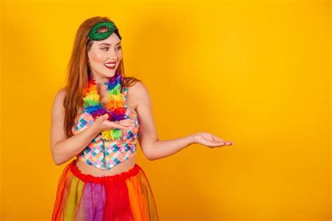 Hermosa chica brasileña pelirroja vestida de carnaval presentando algo a la derecha Foto Premium