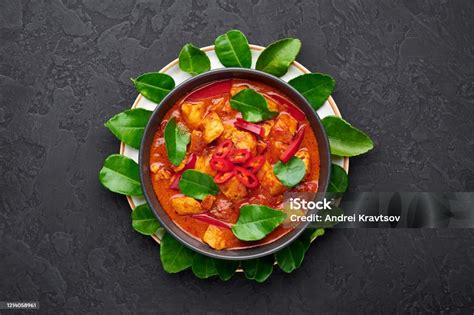 어두운 슬레이트 배경에 검은 그릇에 타이어 파낭 치킨 카레 파나엥 카레는 닭고기 카피르 라임 잎 붉은 카레 소스와 야채를 곁들인 태국 요리 요리입니다 태국 음식 태국 식사