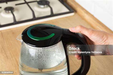 주방의 나무 테이블에 있는 현대적인 전기 투명 주전자 물을 끓이고 차를 만들기위한 주전자 뜨거운 음료를 만들기위한 가전 제품 복사 공간 텍스트를 위한 장소입니다 가정 생활에