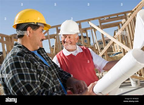 Construction Workers Observing Plans On Construction Site Stock Photo
