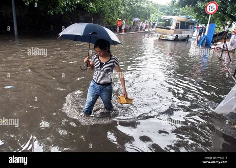 A Chinese Woman Walks Through A Flooded Street Amid Heavy Rain In